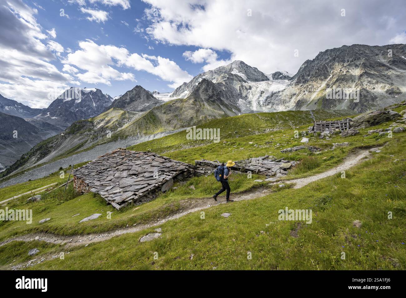 Mountaineers on a hiking trail, Alpine huts covered with slate slabs ...