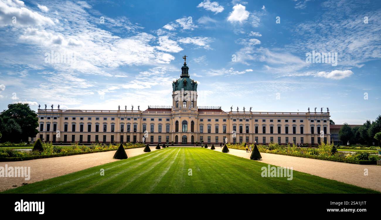A grand palace with a large lawn and neatly trimmed hedges under a blue ...
