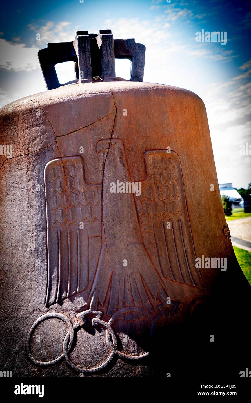 A close-up view of a large, cracked bronze bell featuring an eagle ...