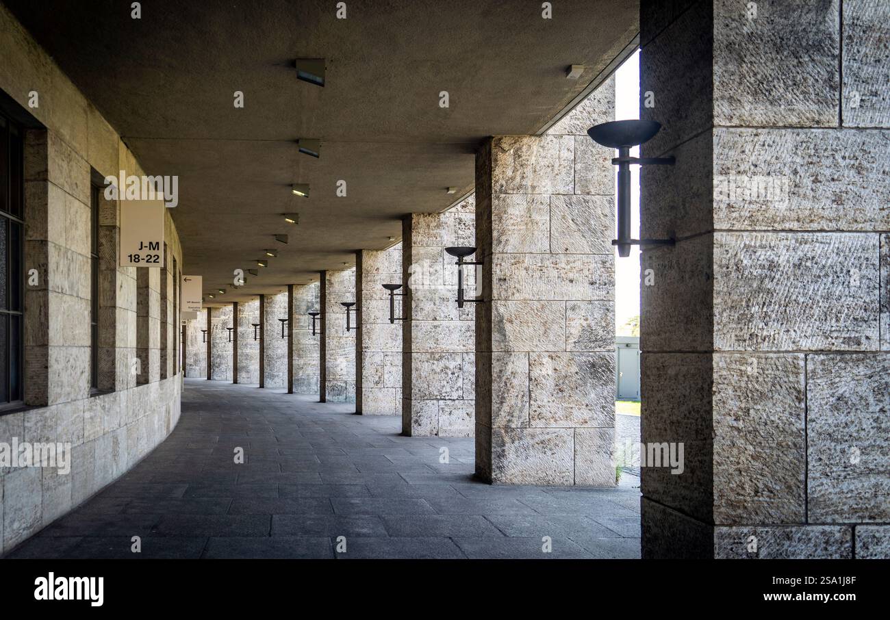 A long corridor with stone columns and modern lighting fixtures. The ...