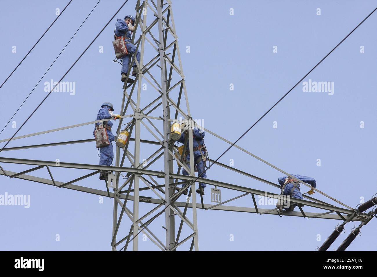 Industrial climber high up on an electricity pylon, workers wearing ...