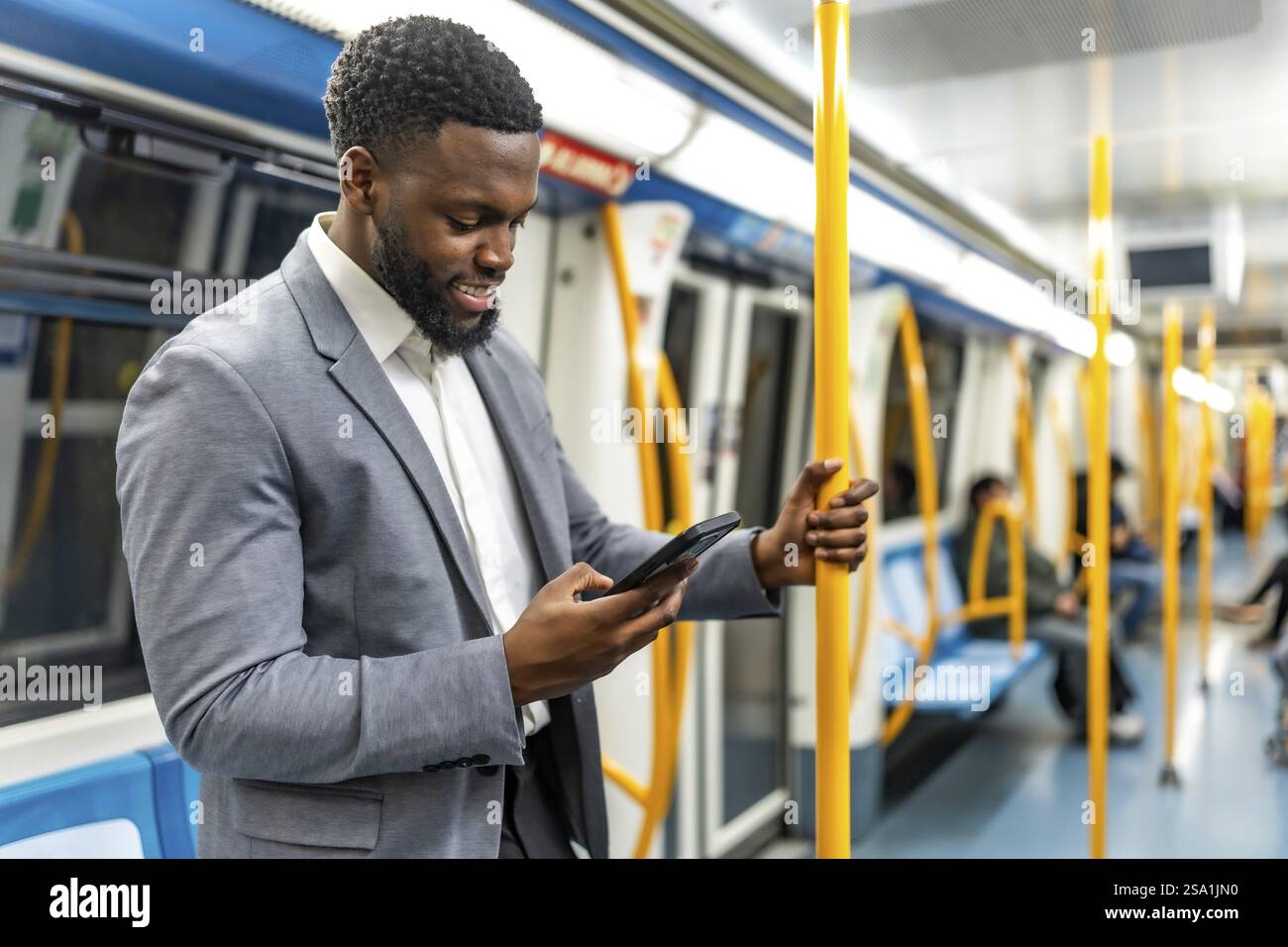 Smiling businessman holding a pole while using a smartphone, standing ...
