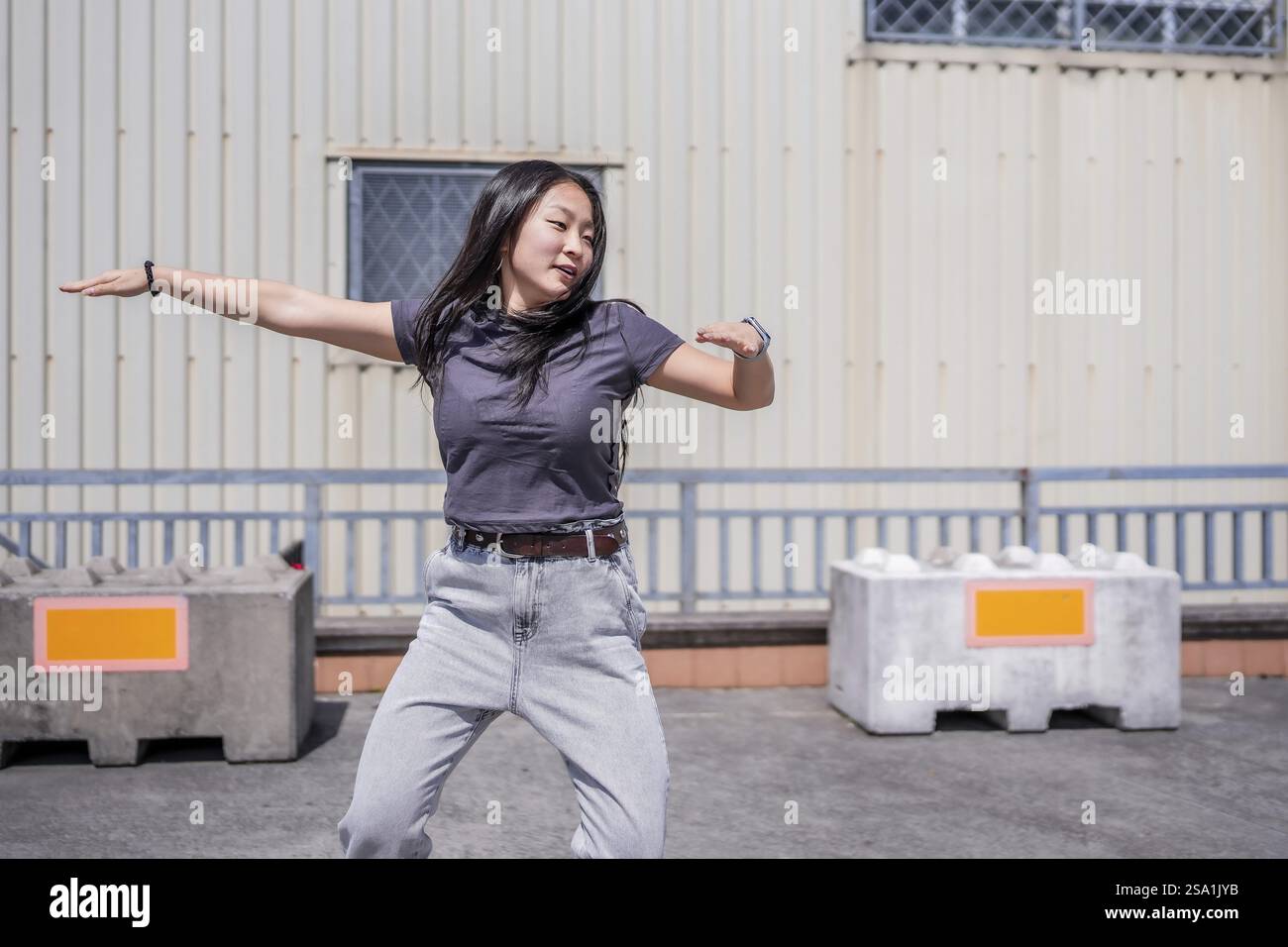 Female young asian K-pop dancer moving energetically in an industrial ...