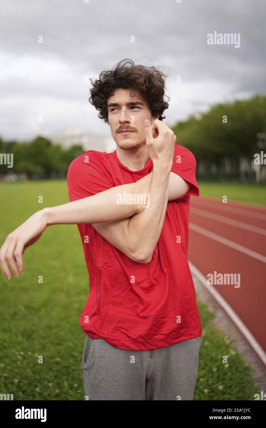 Vertical photo of a caucasian young serious skinny man stretching ...