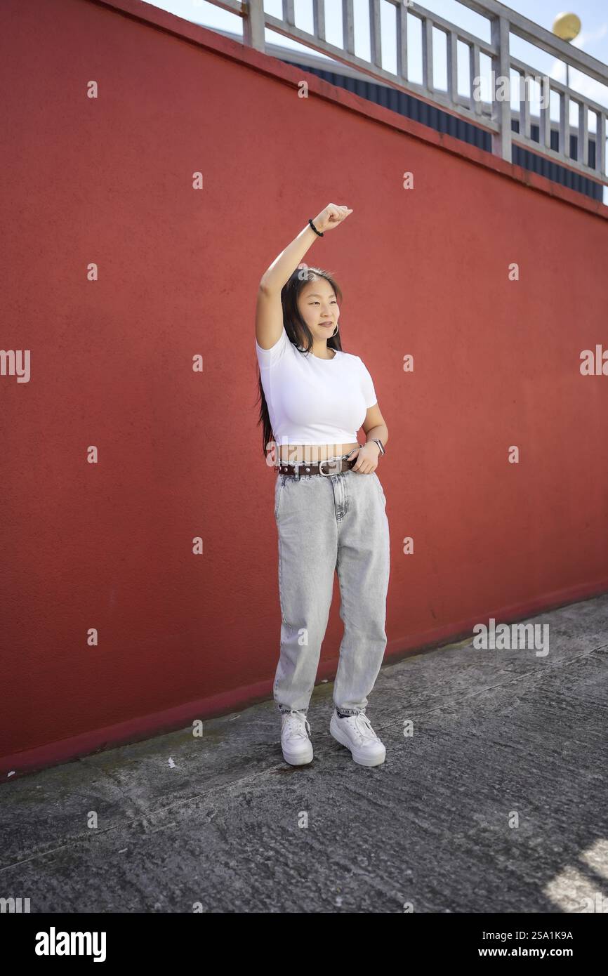 Vertical photo of a cute asian female dancer raising arm performing ...