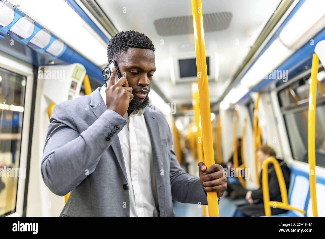 Young businessman having phone call while commuting on subway train ...