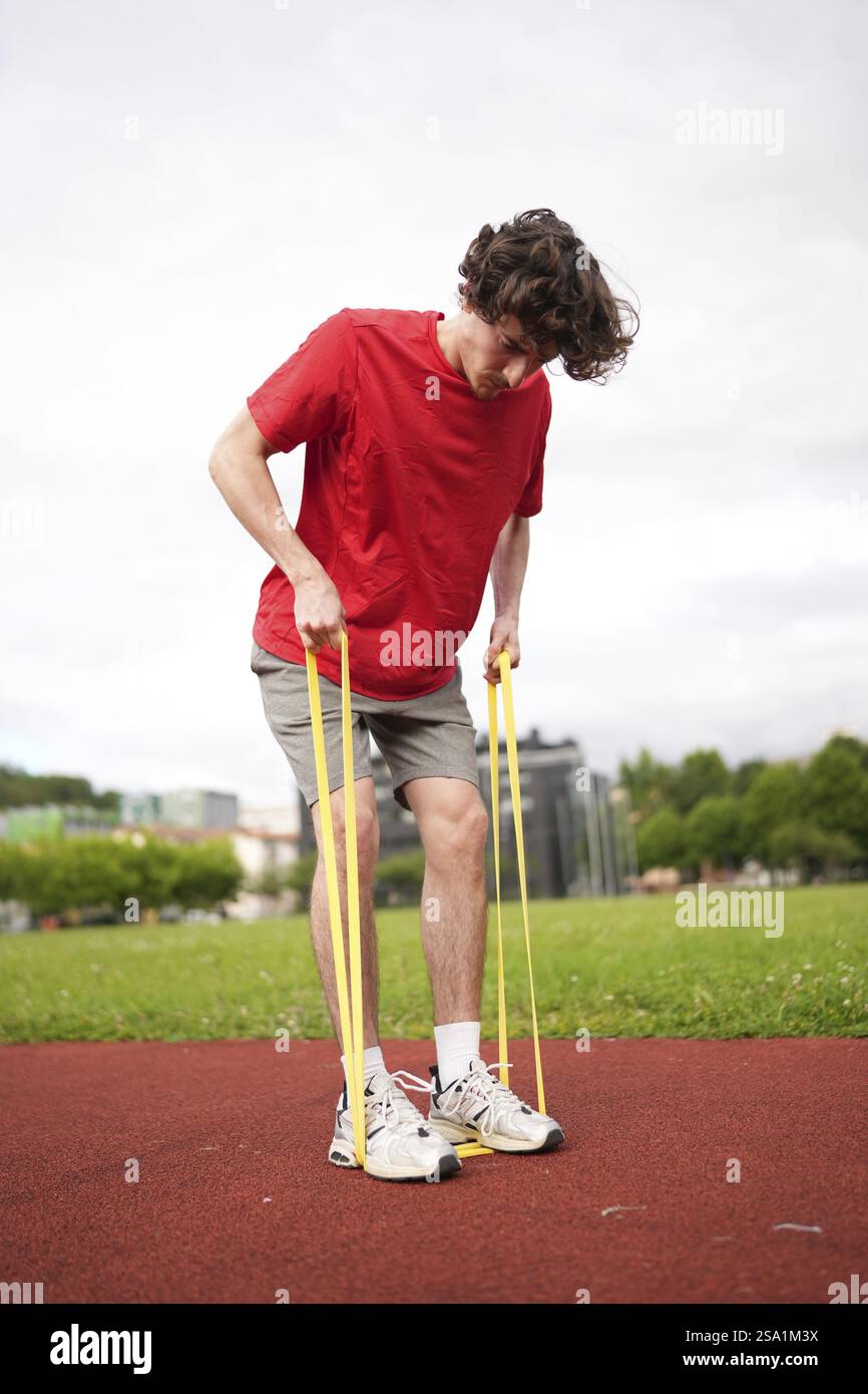 Vertical photo of a caucasian young athlete warming up using resistance ...