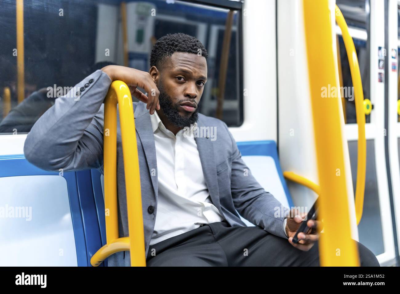 Young businessman engaging with smartphone while commuting on subway ...