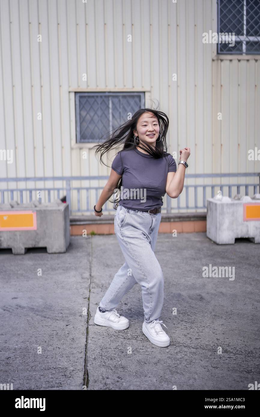 Vertical photo of an asian young woman stepping aside dancing urban ...