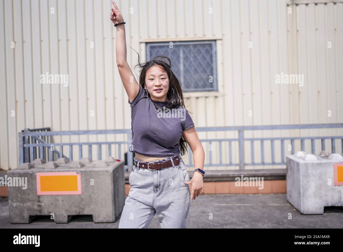Asian young woman pointing to the sky dancing k-pop urban dance outside ...
