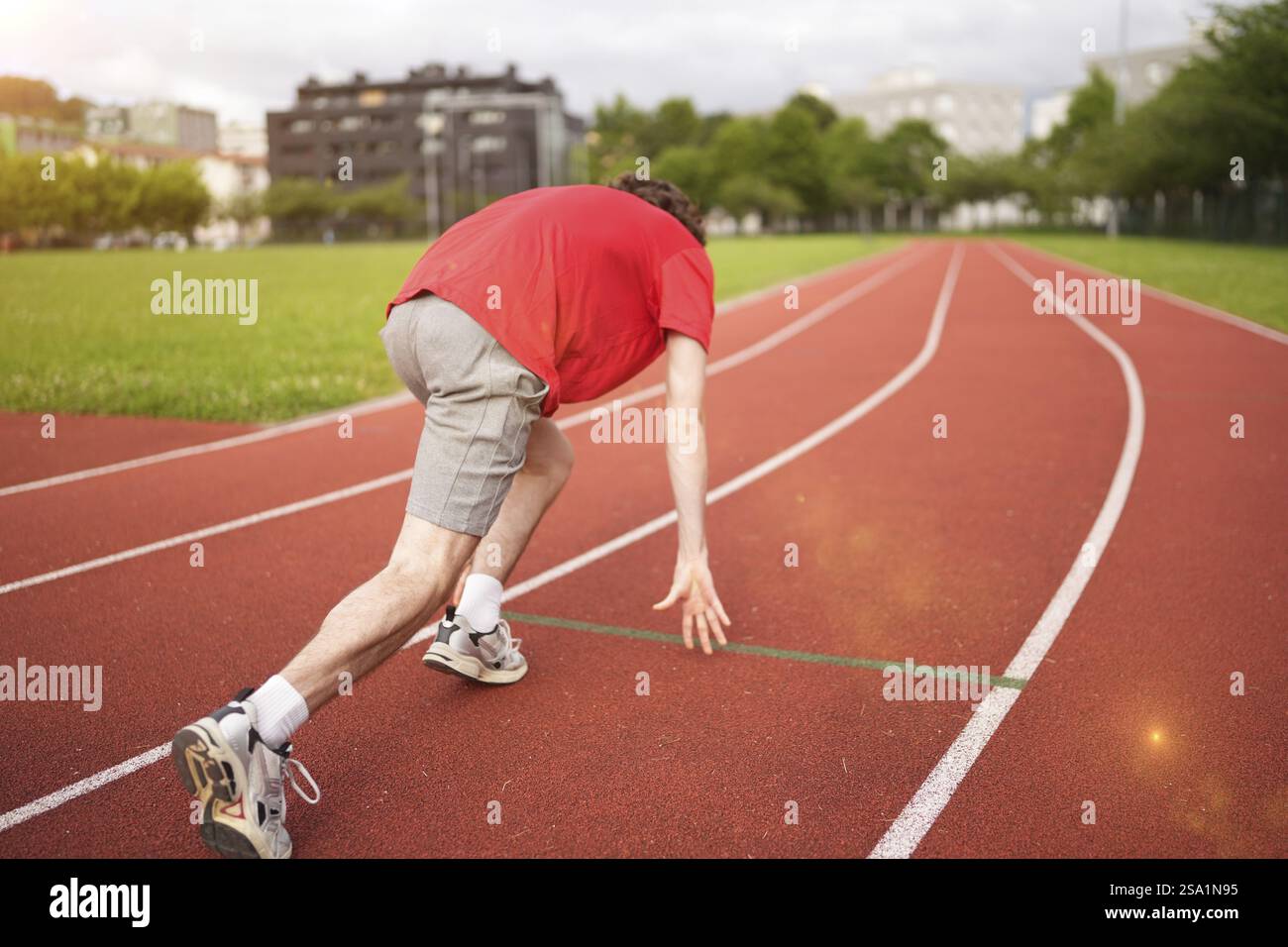 Rear view of a male caucasian young runner on running track starting ...