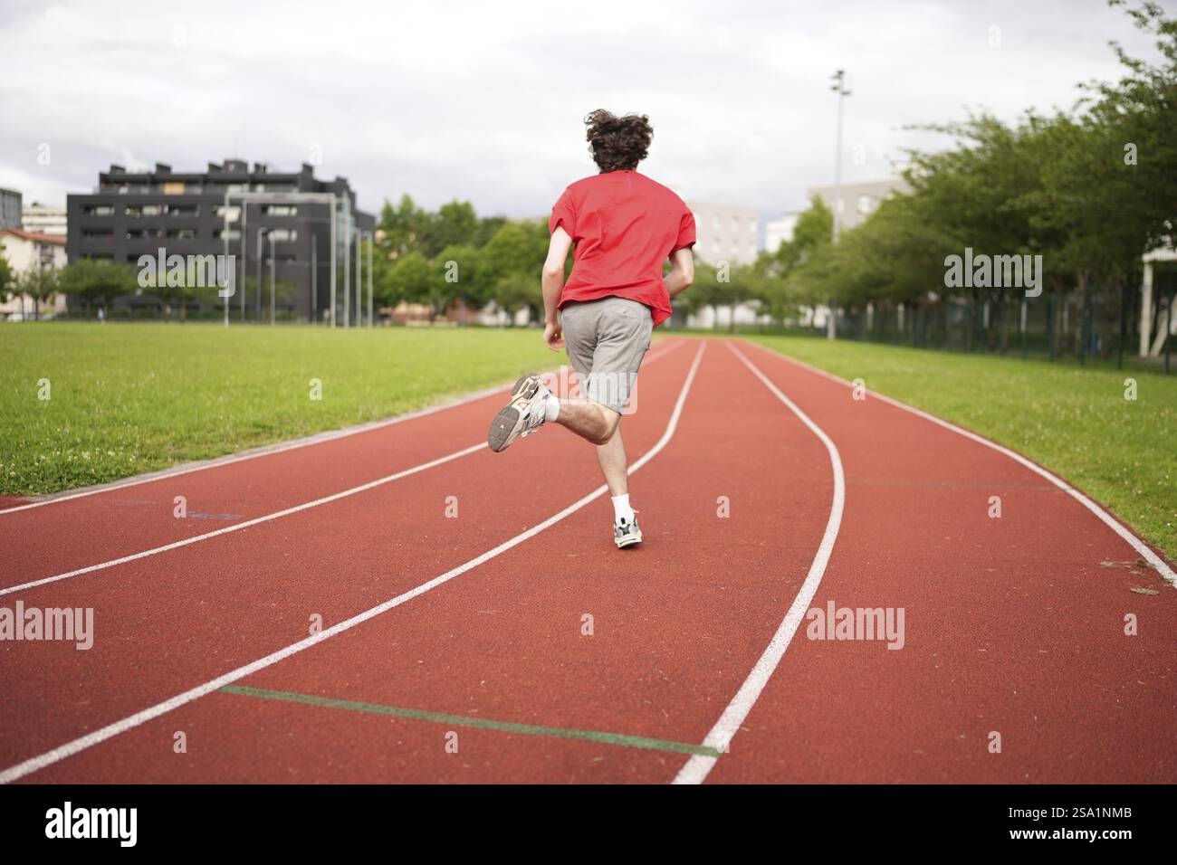 Full length rear view of a casuasian male young athlete sprinting ...