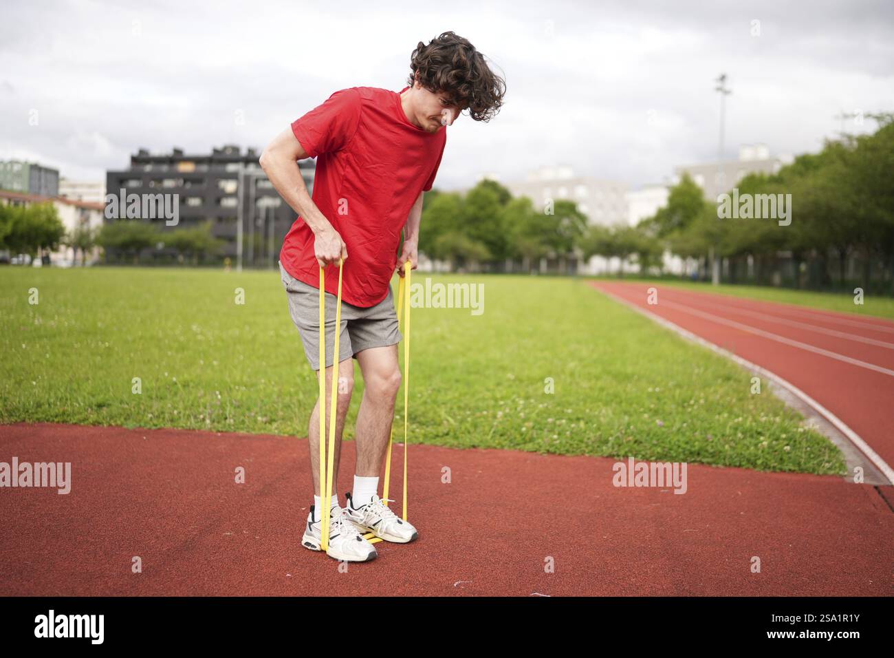 Young caucasian man training outdoors in a running track by doing ...