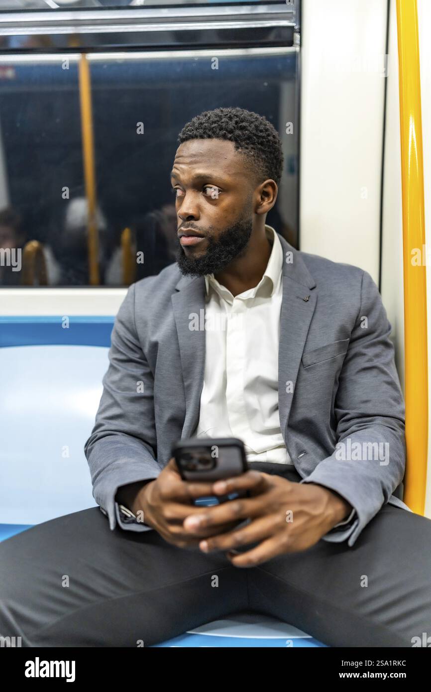 Young businessman commuting on a subway train, using a smartphone to ...