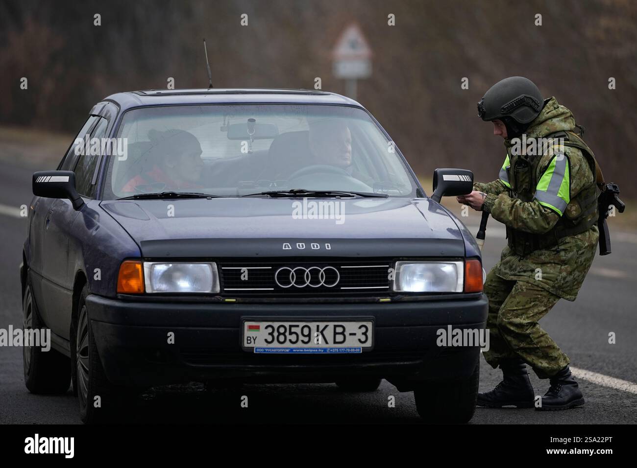 A Belarusian border guard inspects a car on the road at Teryukha ...