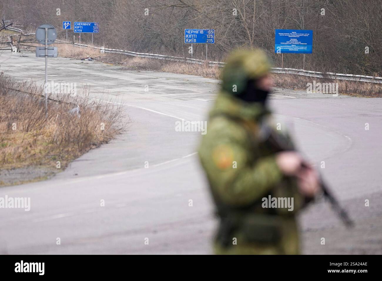 A Belarusian border guard inspects a road outside of Ukrainian border ...