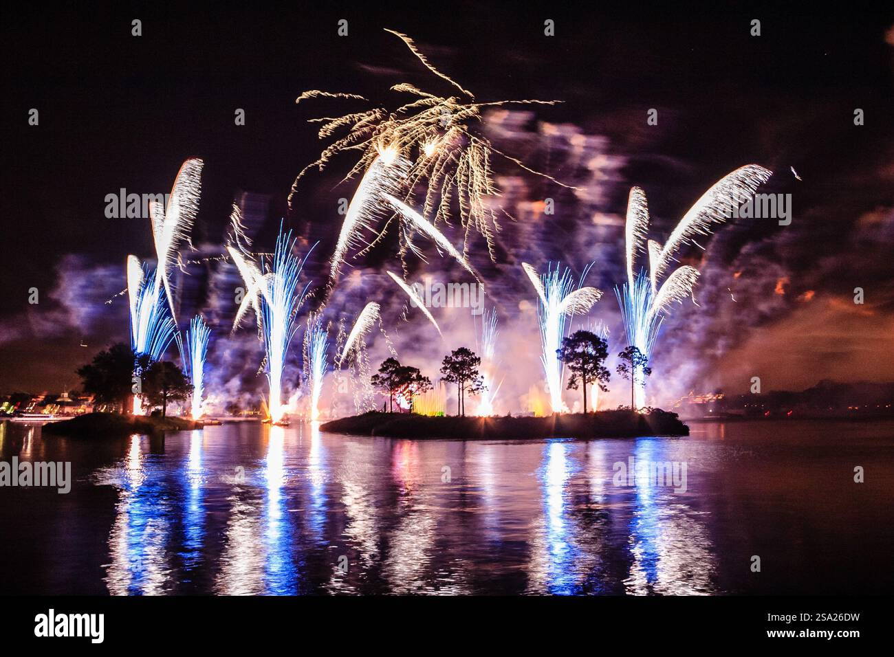 A fireworks display is lit up in the night sky over a body of water ...