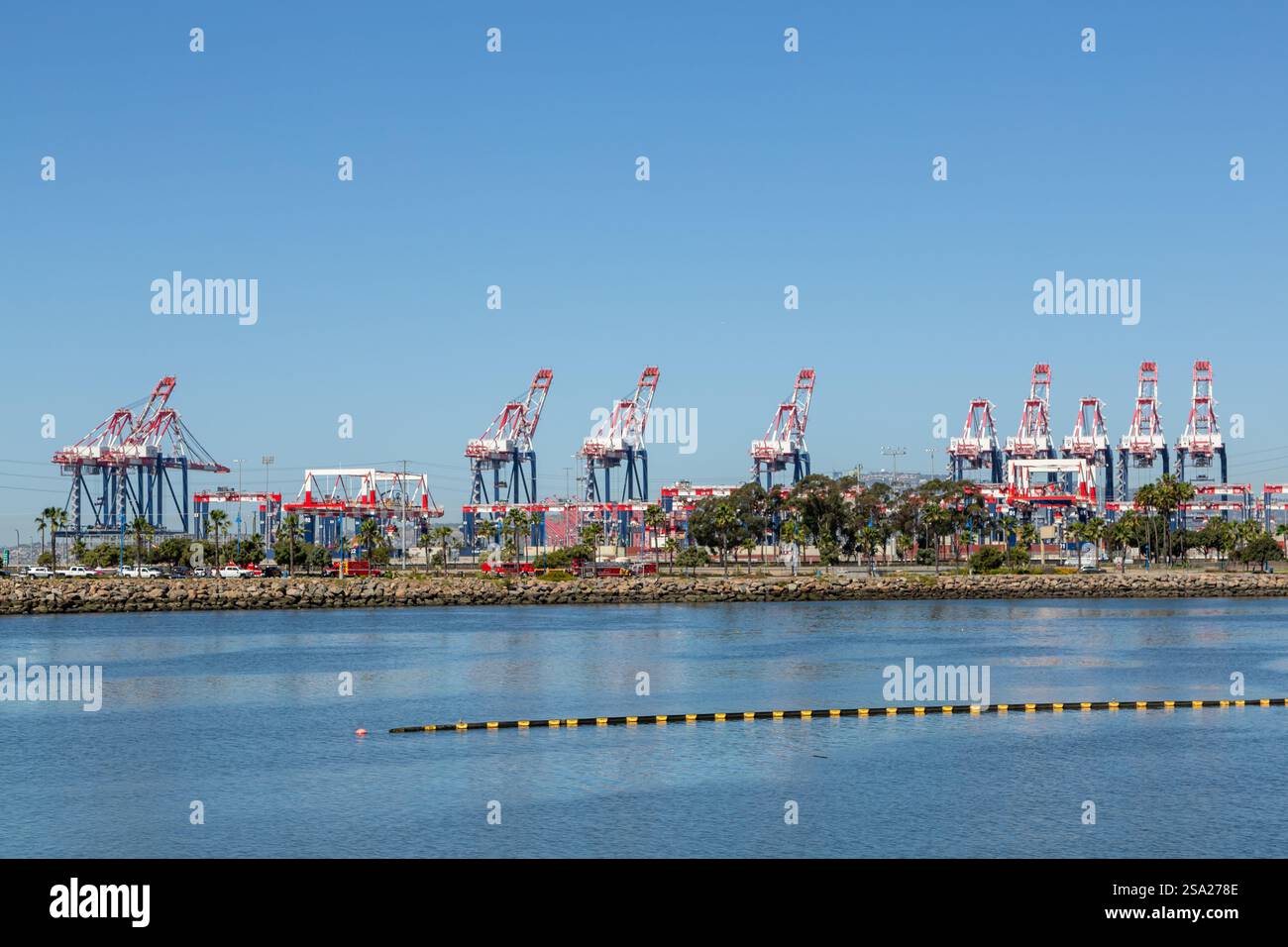 Large industrial port cranes stand tall at a busy shipping dock ...