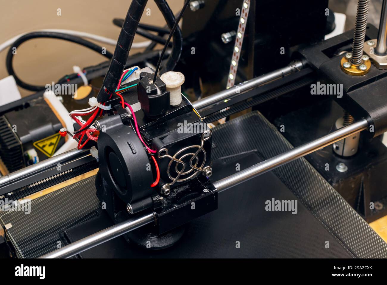 This is a detailed closeup view of a 3D printer equipped with a cooling ...