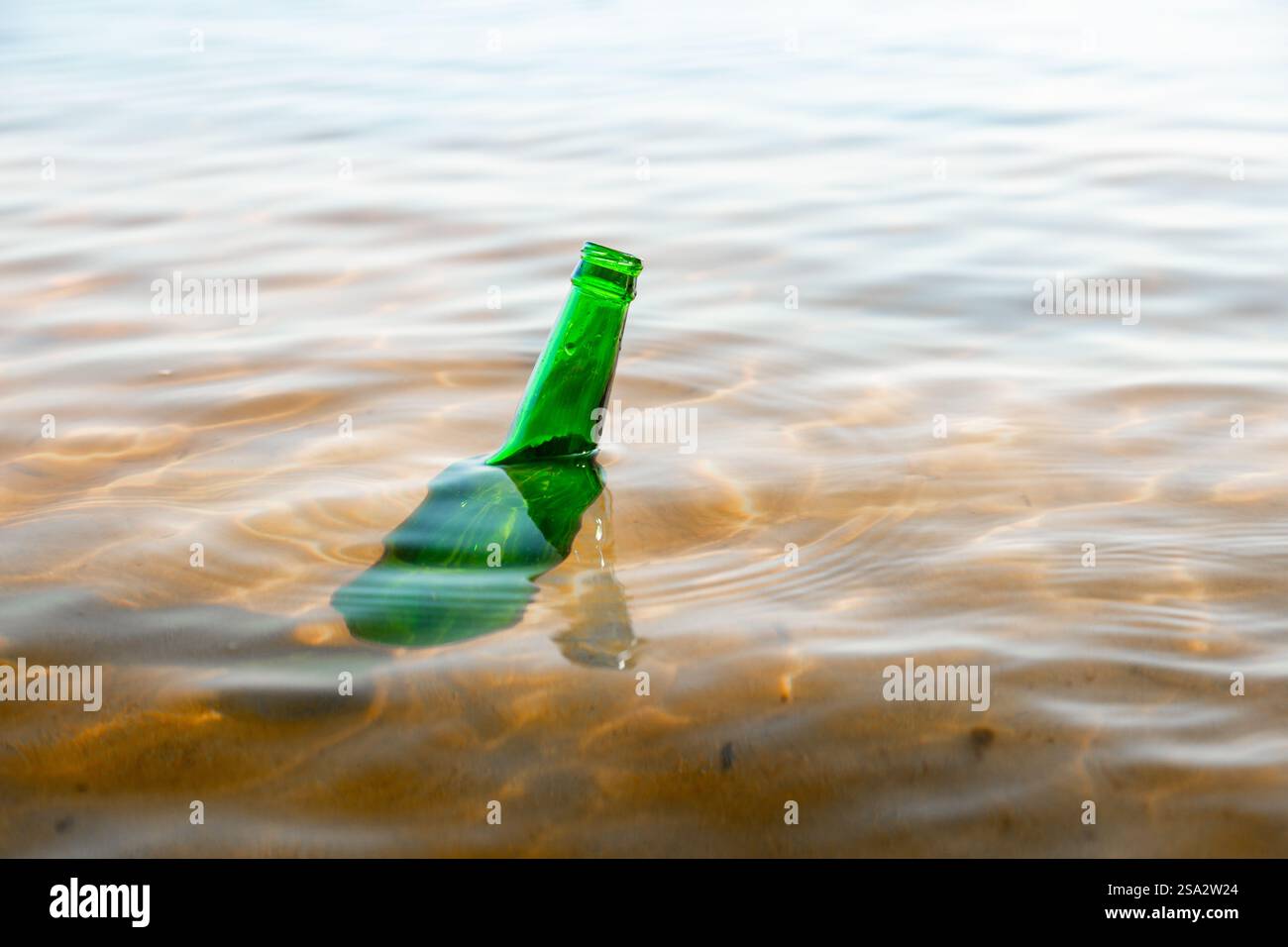 Green glass bottle floating in a river, bottleneck seen over water ...