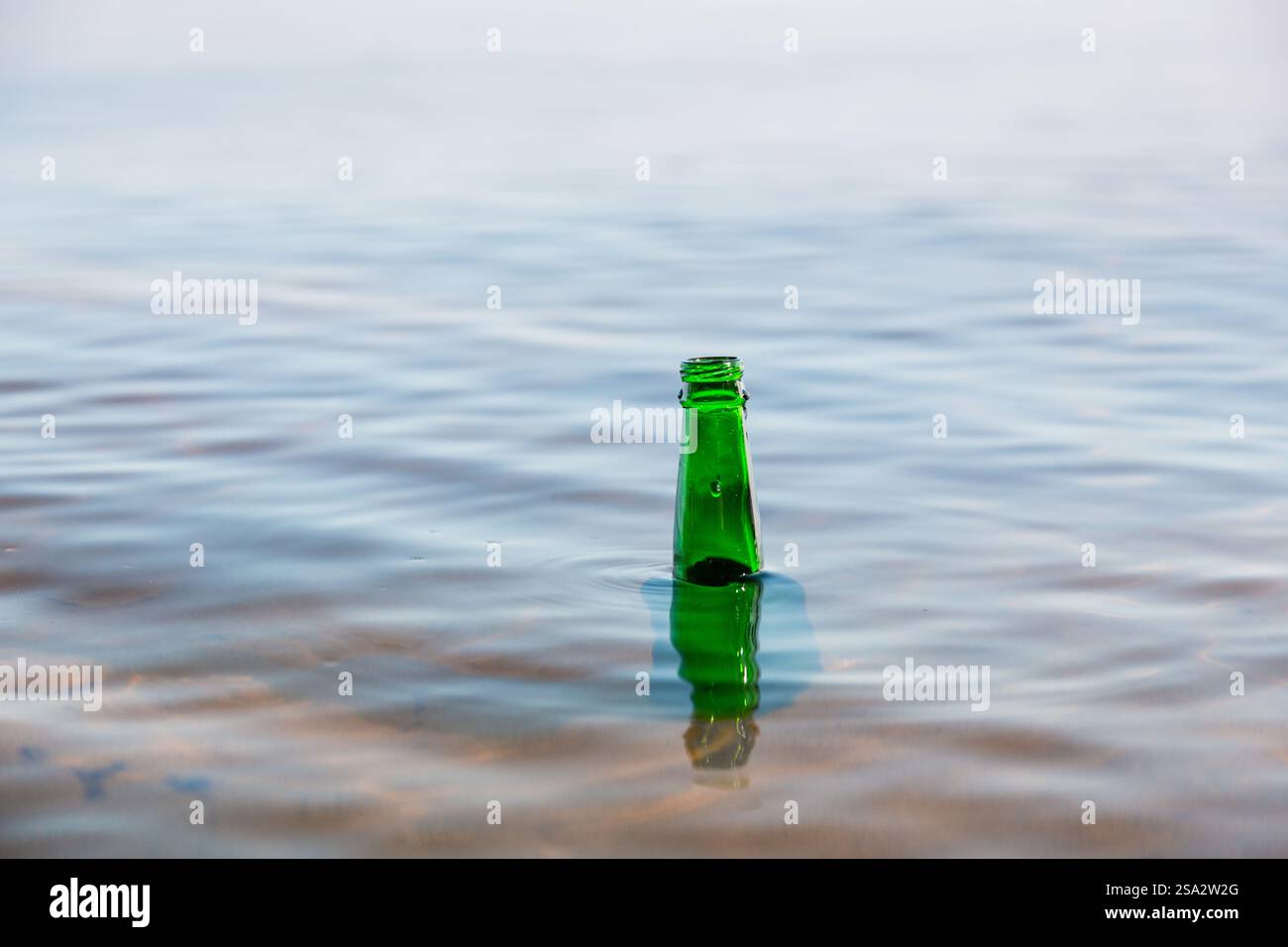 Green glass bottle floating in a river, bottleneck seen over water ...