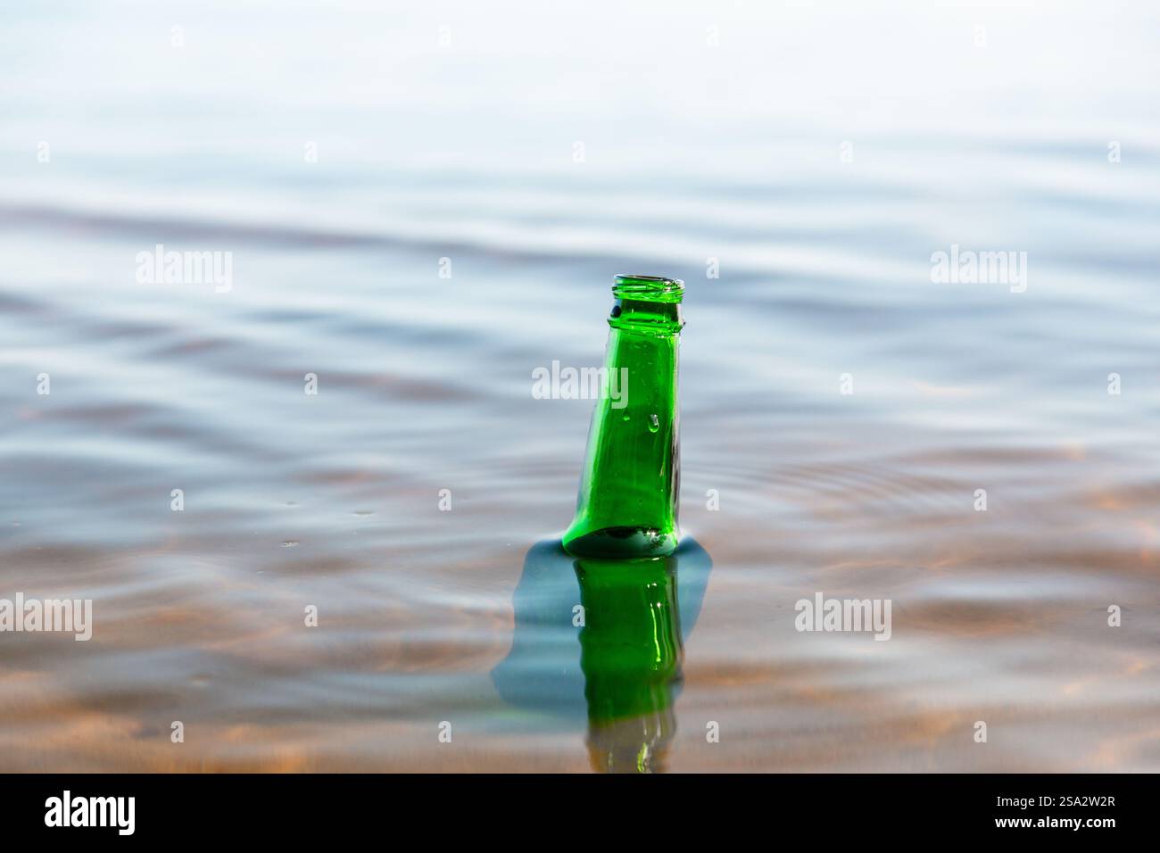 Green glass bottle floating in a river, bottleneck seen over water ...