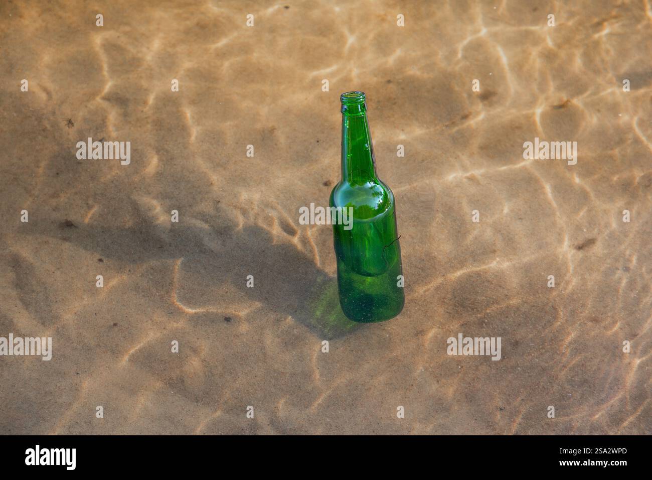 Green glass bottle floating in a river, bottleneck seen over water ...