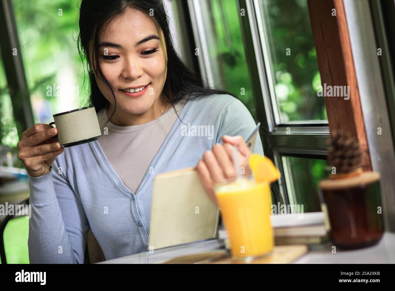 Young Asian woman sitting in cafe reading a book Stock Photo - Alamy
