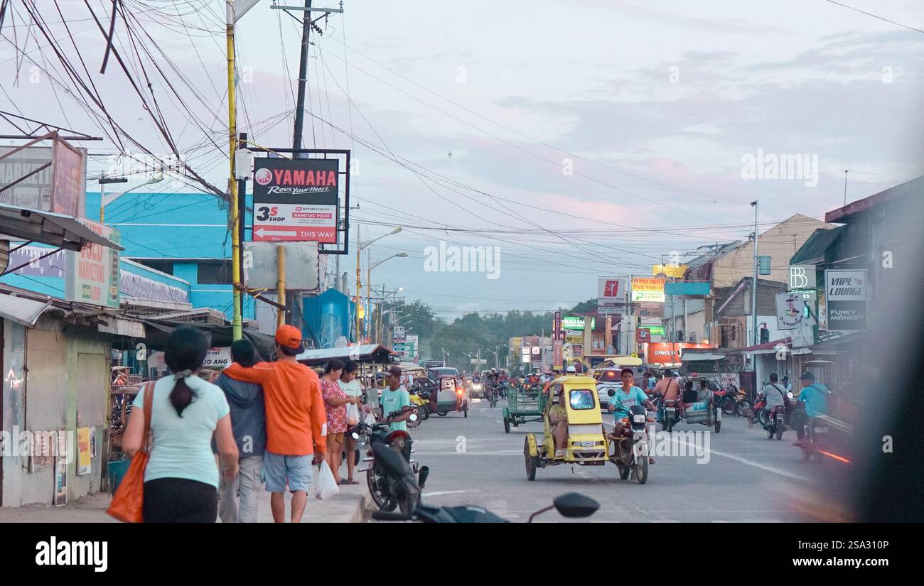 A lively evening street in Iloilo, Philippines, filled with jeepneys ...
