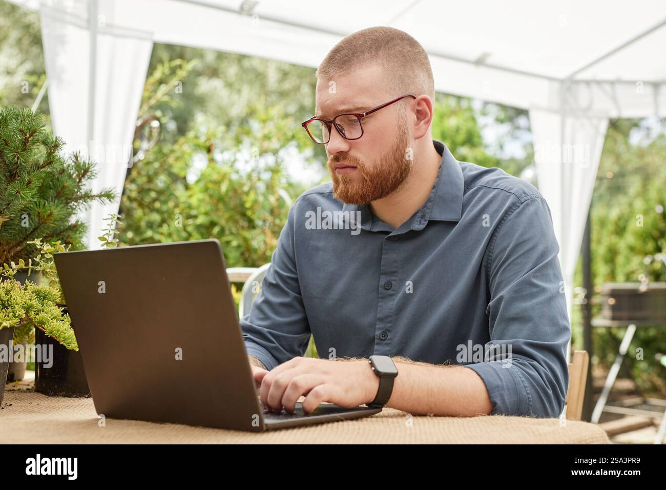 Medium shot of concentrated male landscape designer typing on laptop ...