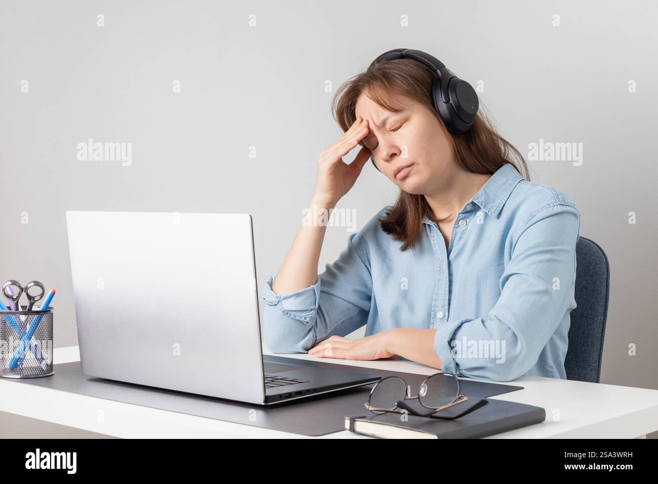 An overworked female freelancer is tired and stressed behind her laptop ...