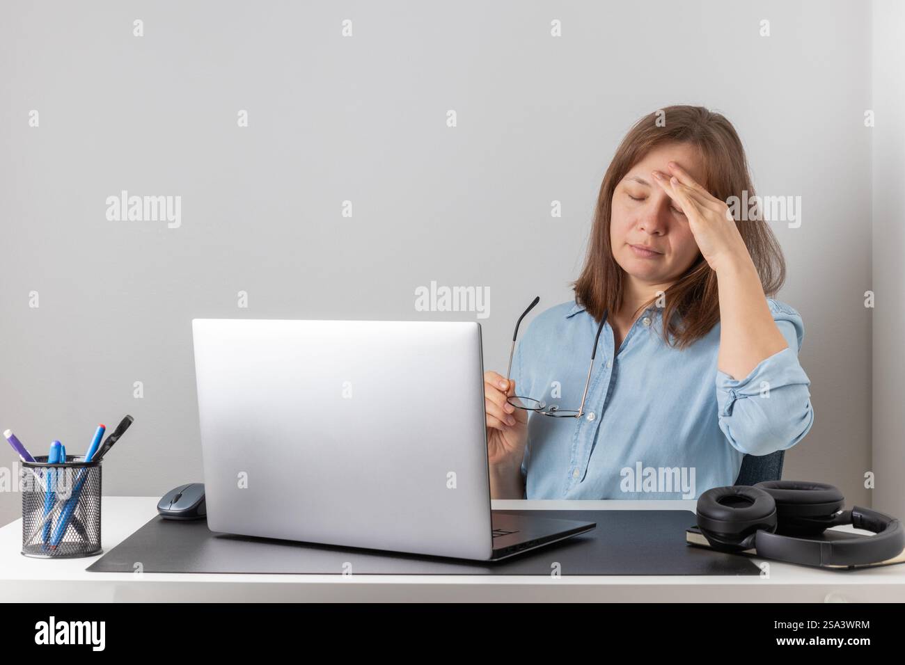 An overworked female freelancer is tired and stressed behind her laptop ...