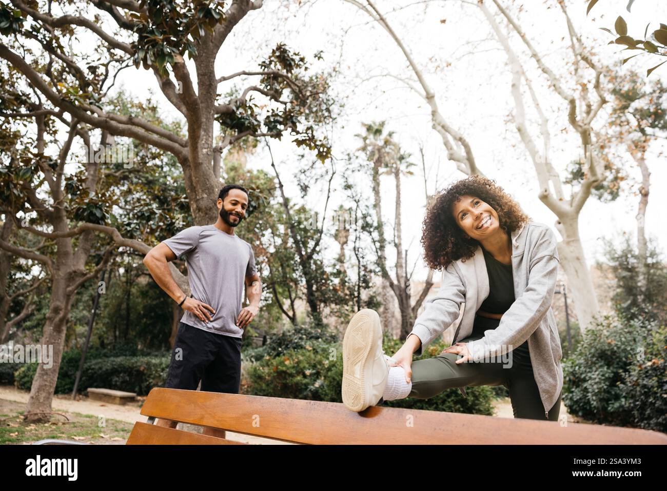 Fitness coach assisting a woman in stretching exercises outdoors in a ...