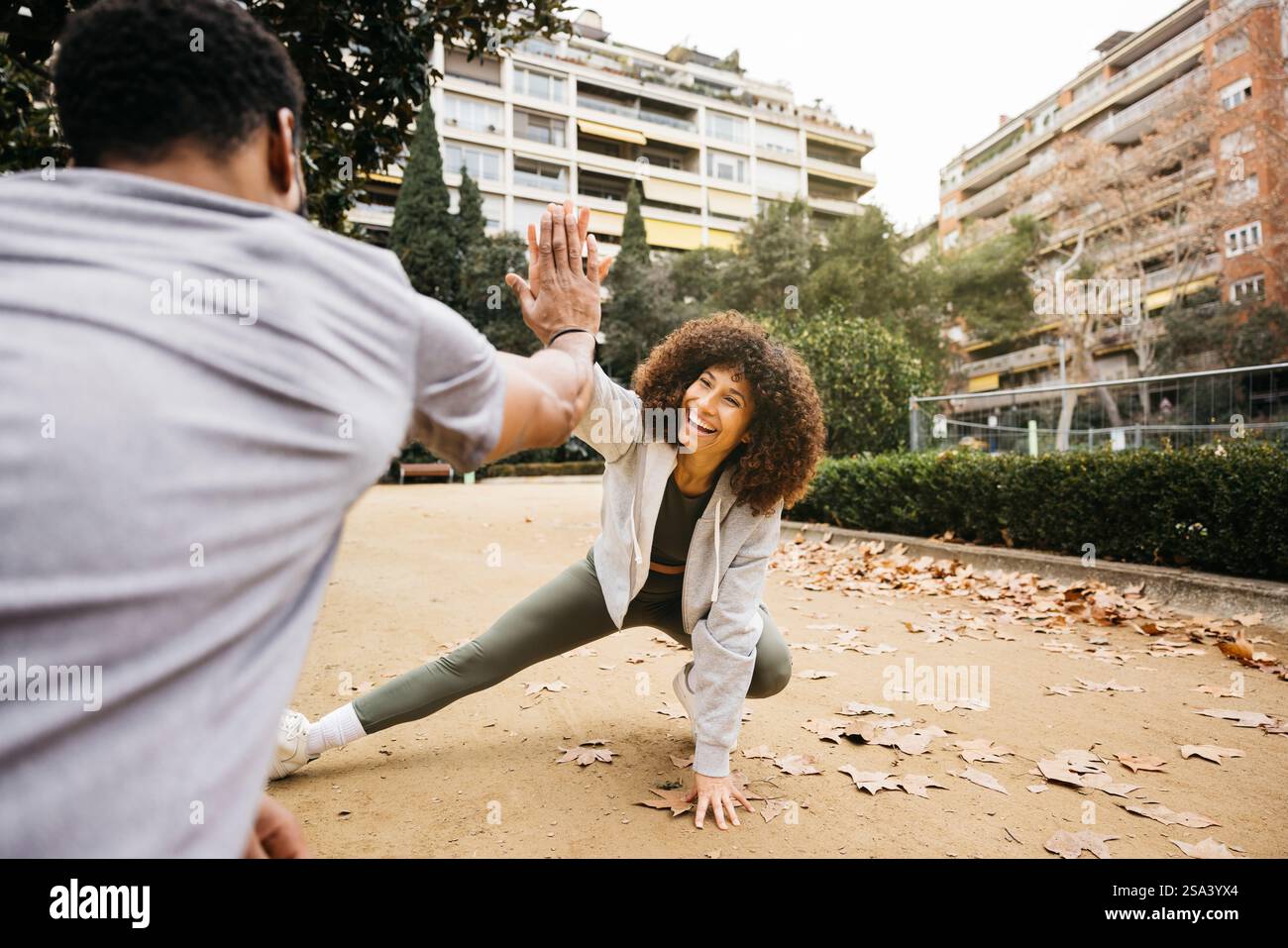 A fitness trainer motivates his client by high fiving during an outdoor ...