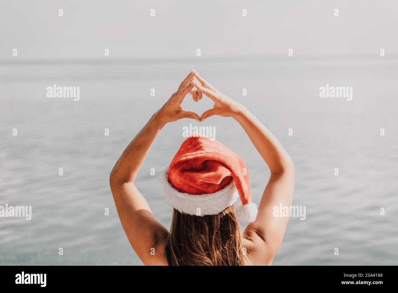 A woman wearing a red Santa hat is holding her hands together in a ...