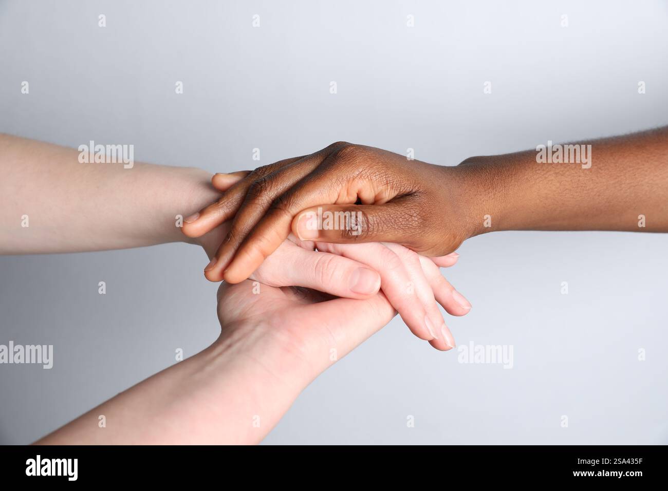 Stop racism. People of different skin colors holding hands on light ...