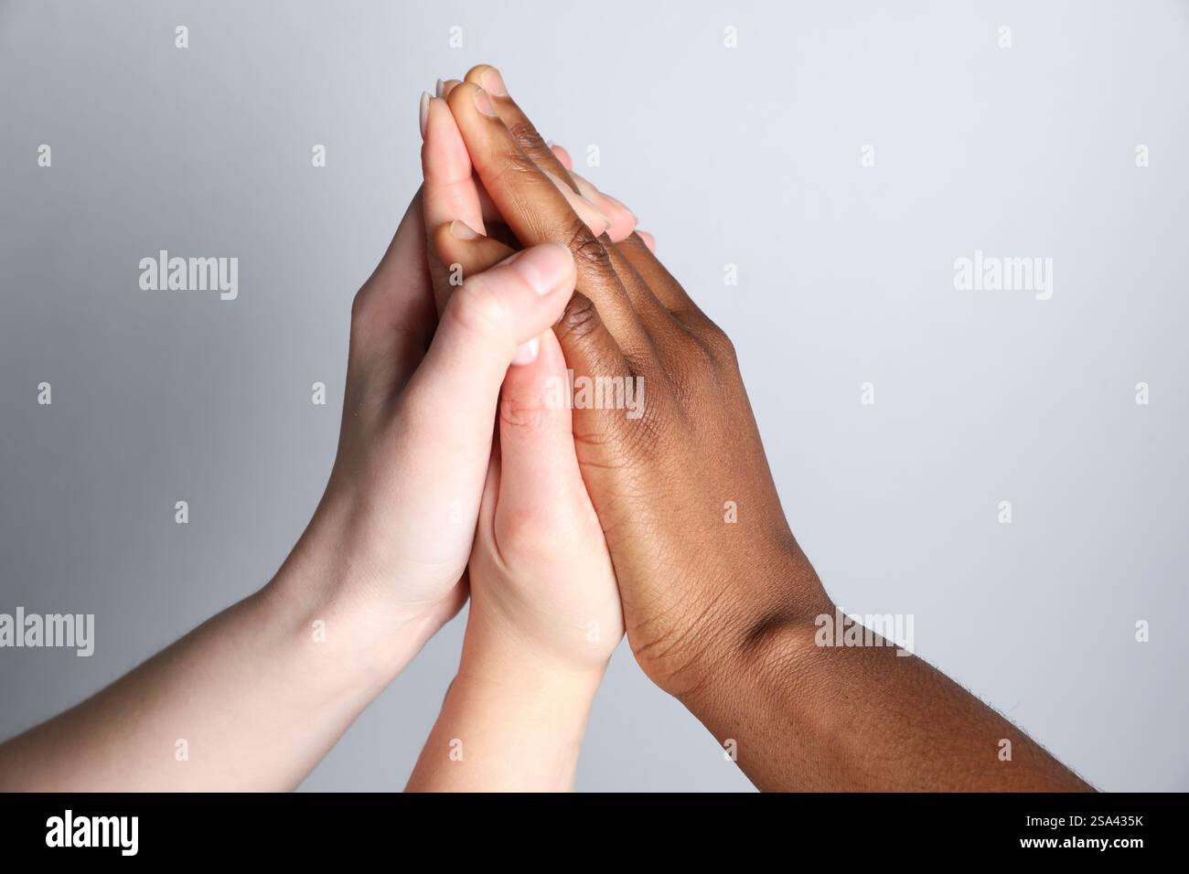 Stop racism. People of different skin colors joining hands on light ...