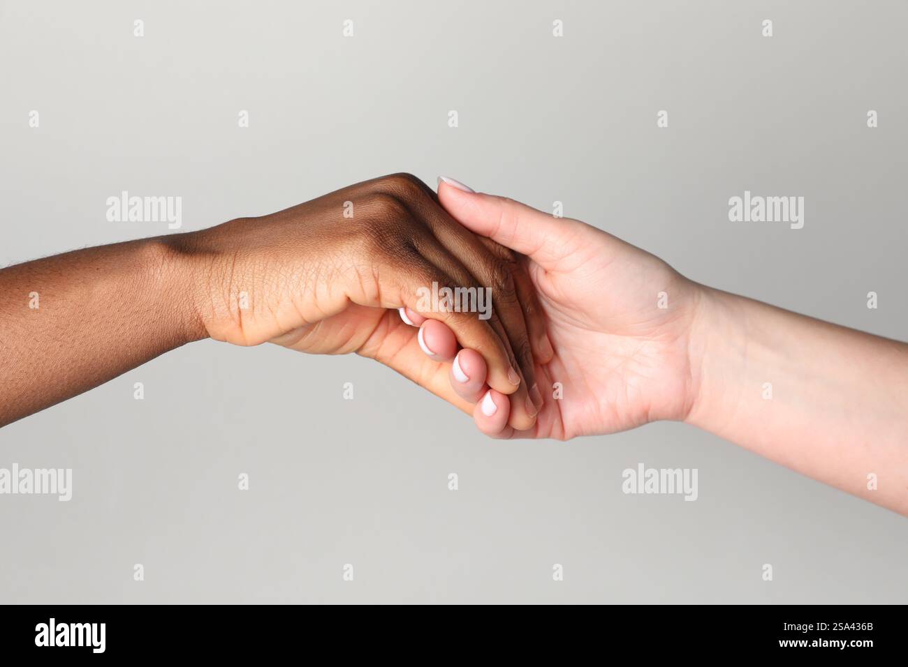 Stop racism. People of different skin colors holding hands on light ...