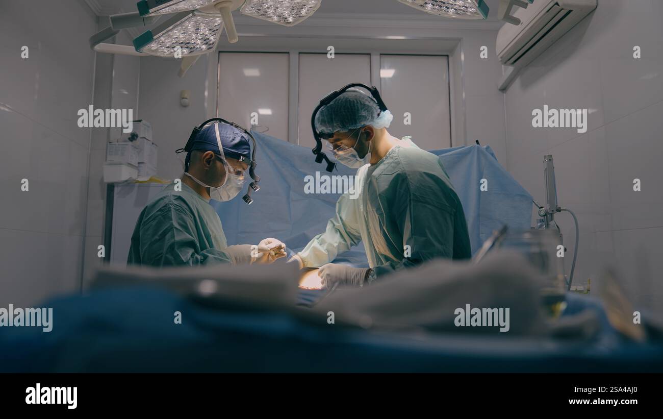 Team of two doctors men surgeons processing surgical operation using ...