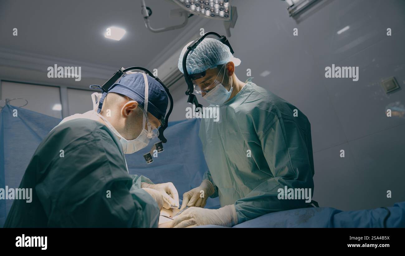 Surgeon doctor with intern practitioner perform surgical operation men ...