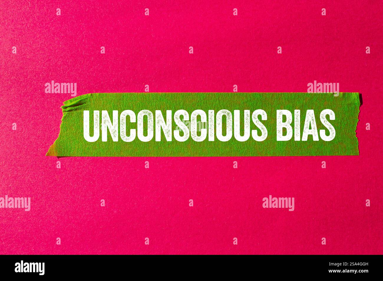 Unconscious bias message written on ripped torn green paper tape on pink background. Conceptual ...