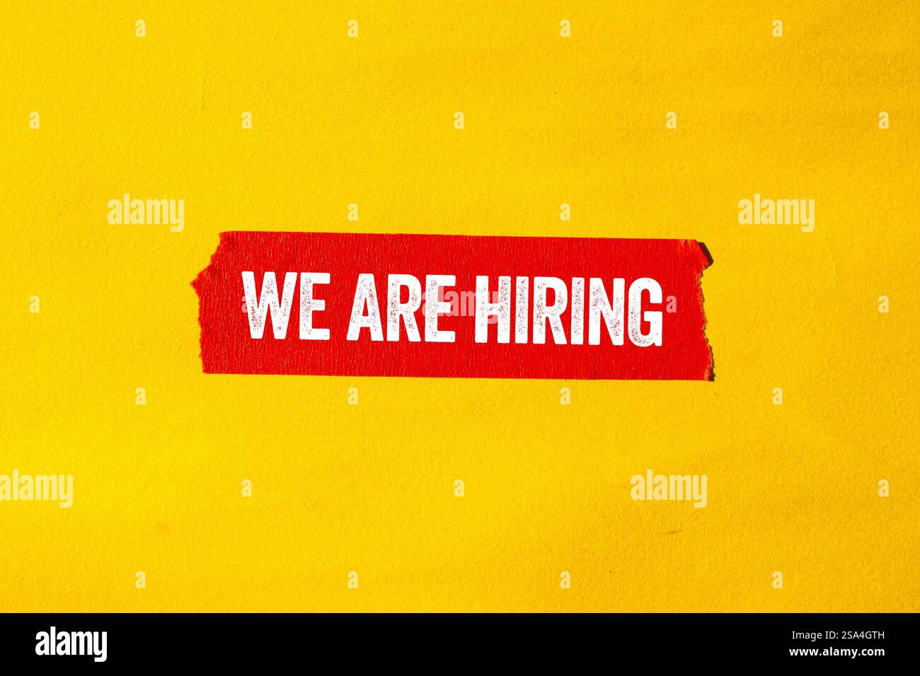 We are hiring message written on ripped torn red paper tape on yellow background. Conceptual we ...
