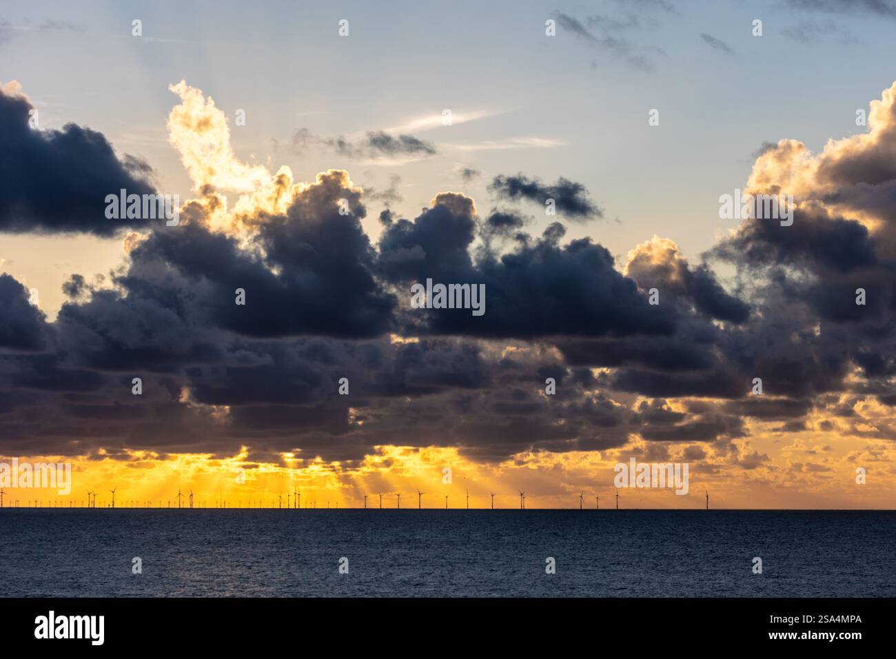 Evening sun behind dark clouds of a thunderstorm over silhouettes of ...