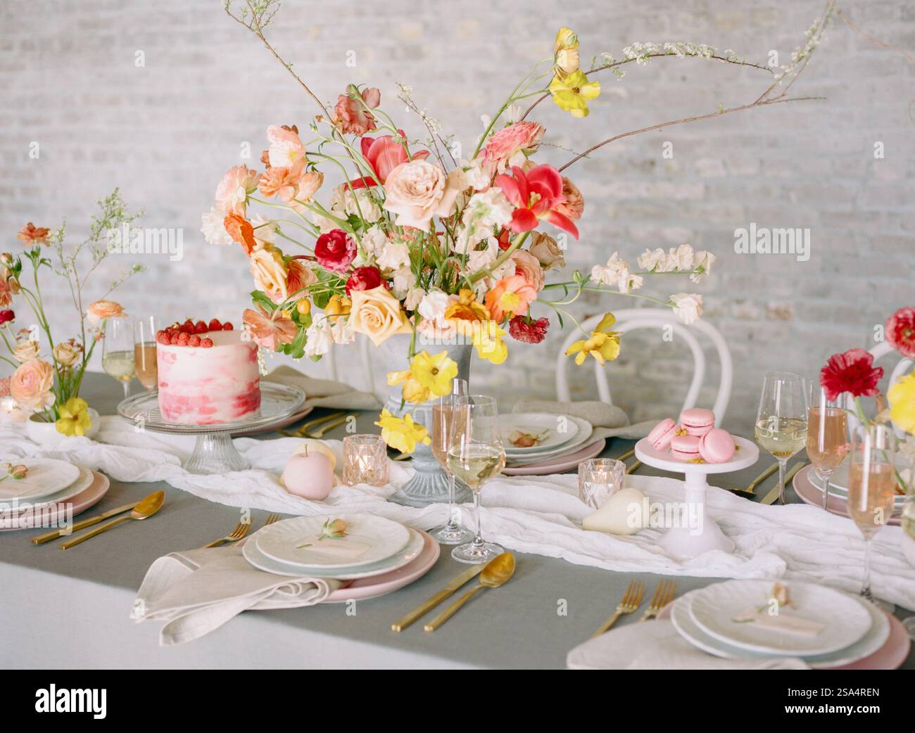 A vibrant floral arrangement features roses and tulips at a neatly set ...