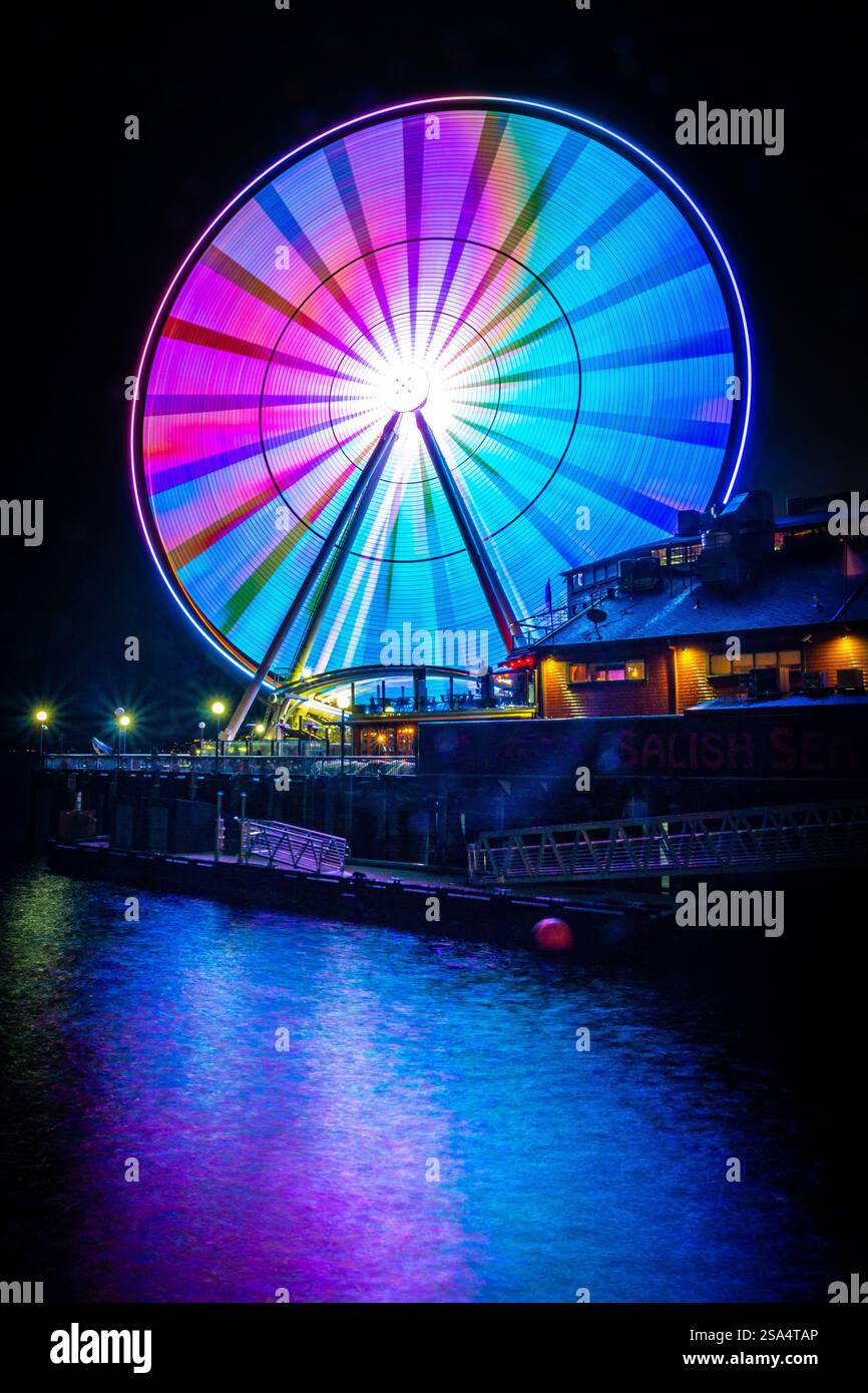 The Seattle Great Wheel glows brightly at night, with colorful ...