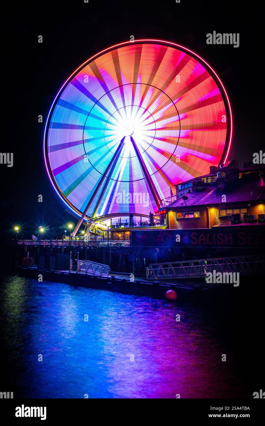 The Seattle Great Wheel glows brightly at night, with colorful ...