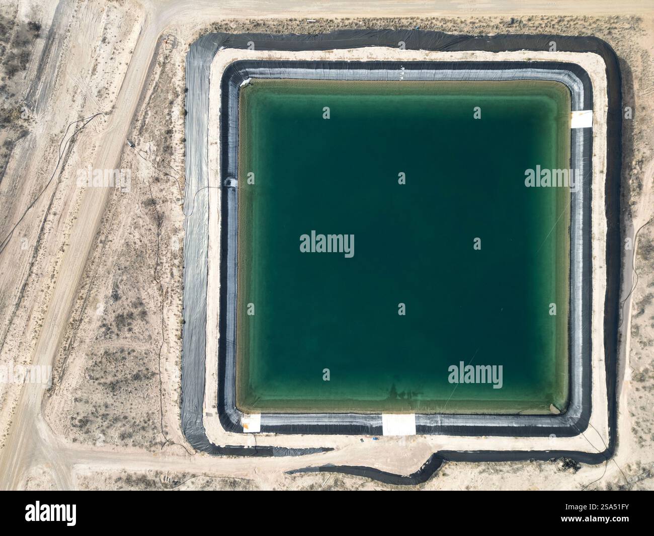 Aerial view looking down on a square water retention pond used in oil production and fracking in ...