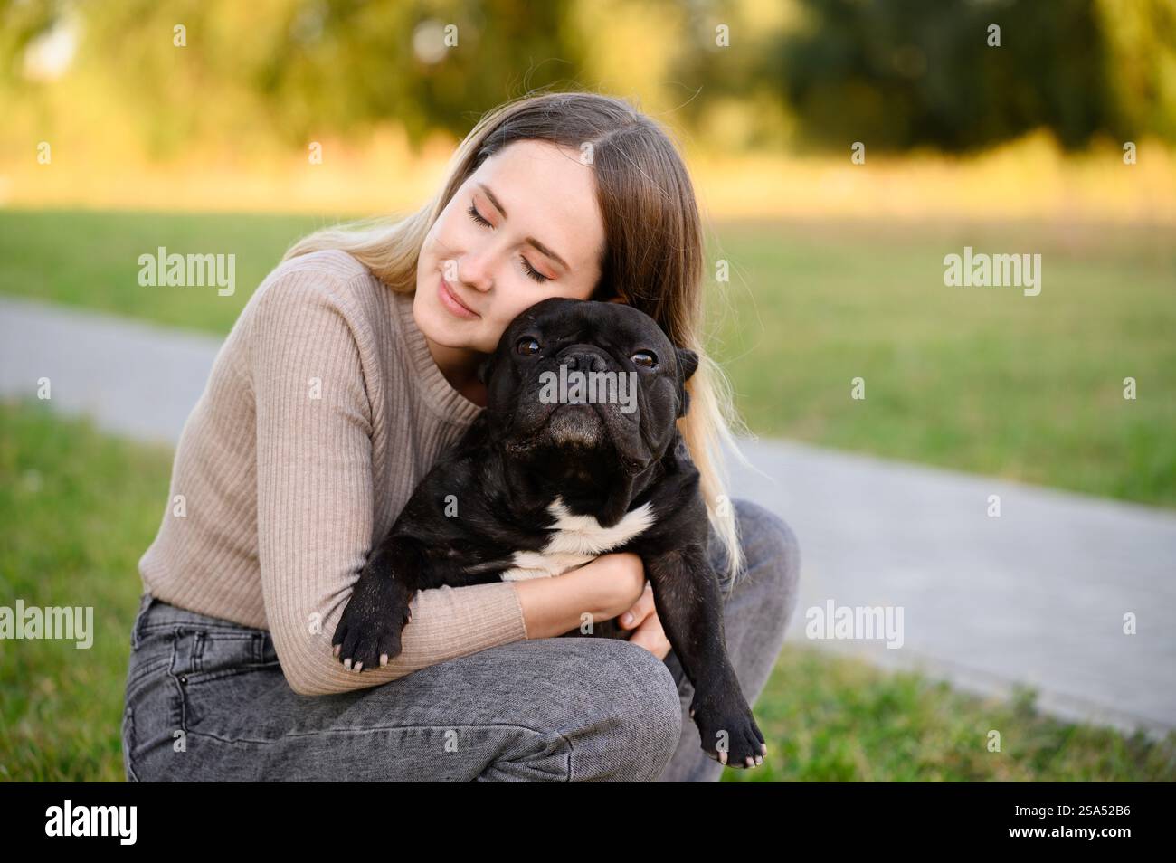 Woman cuddles a black French bulldog adopted from a shelter, hugging ...