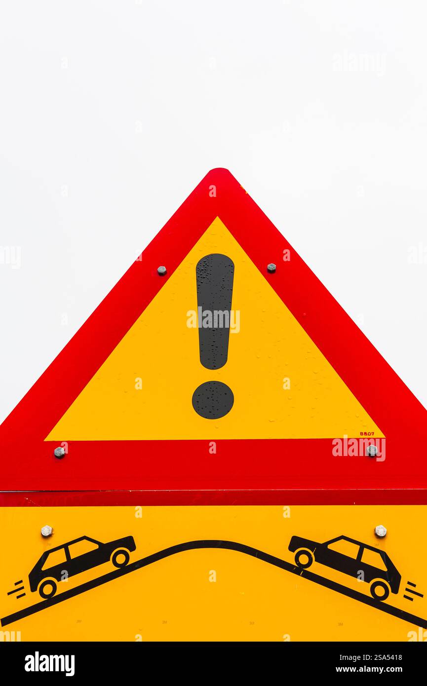 A bright triangular warning sign stands prominently in Iceland ...