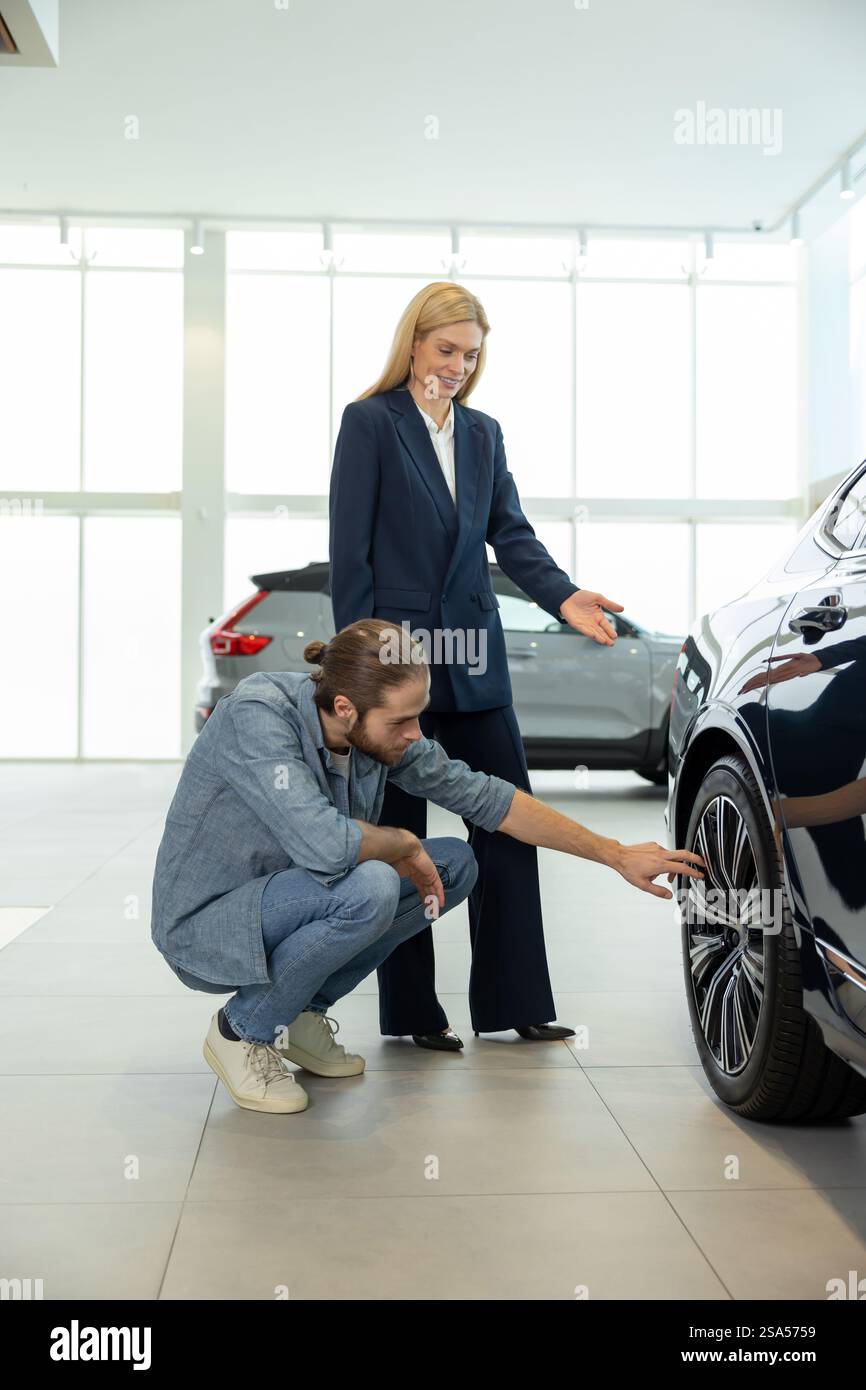 Male client examining wheels of a new car model in a dealership Stock ...